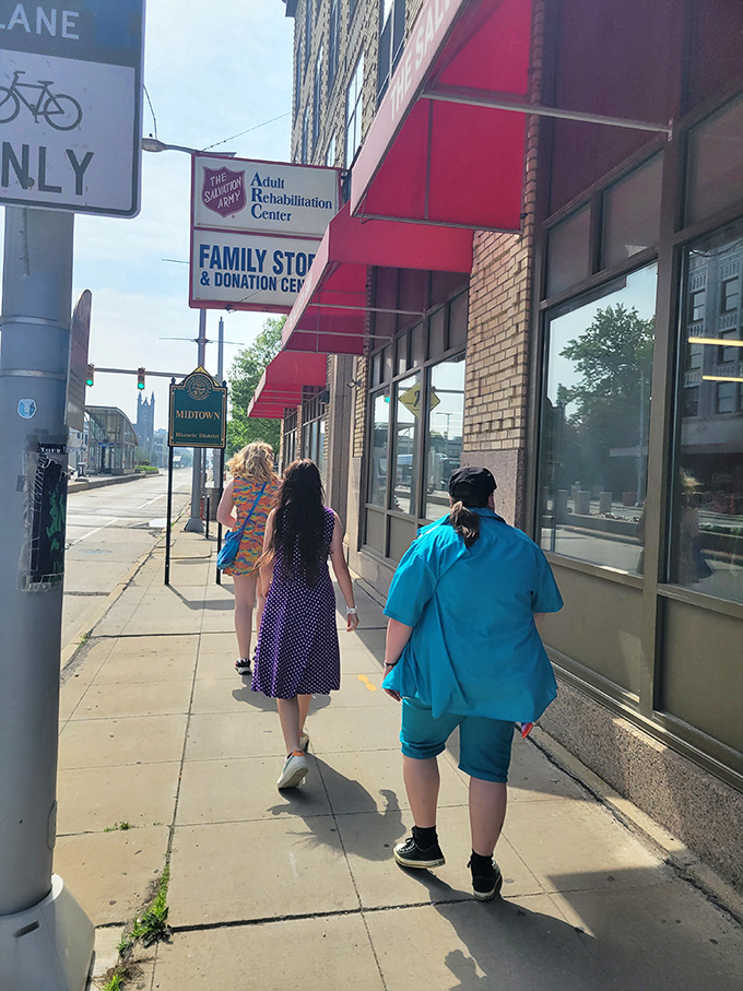 Sidewalk shoppers stroll past the distinctive red awnings, unaware of the vintage treasures waiting just steps away.