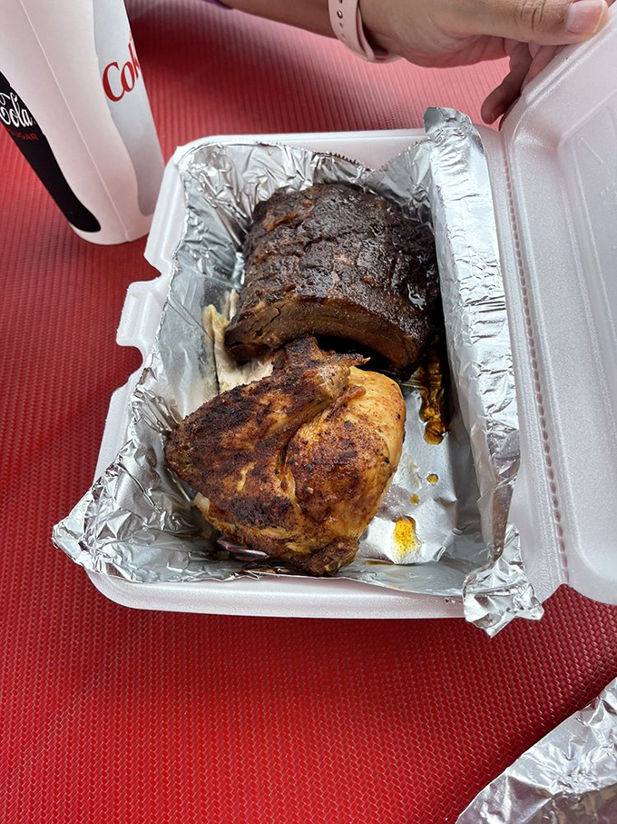 Behold the carnivore's dream team: perfectly smoked chicken and ribs nestled together in their foam container like old friends reuniting for one last delicious adventure.