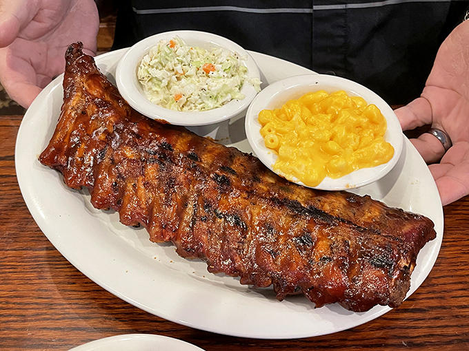 Behold BBQ perfection – a half-rack of ribs with that telltale smoke ring, flanked by creamy slaw and mac & cheese that means business.