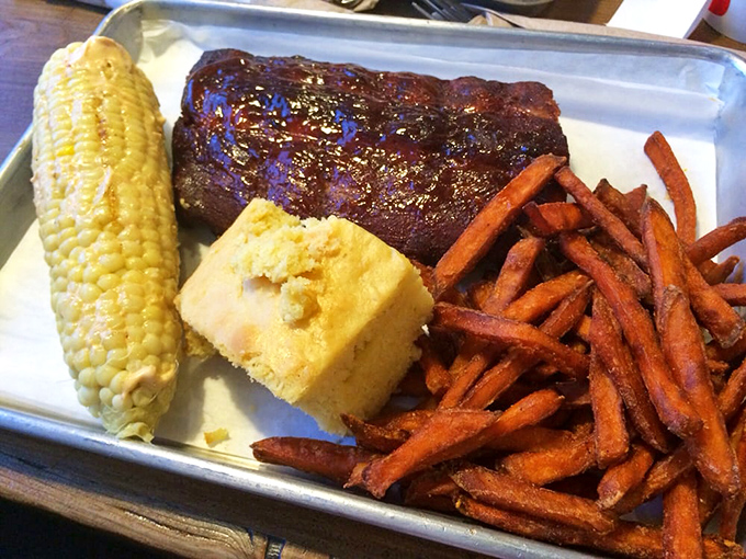Behold the holy trinity: ribs that surrender at first bite, cornbread dreams, and sweet potato perfection.