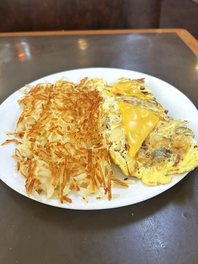 Golden hash browns that crackle with each bite alongside a cheese-laden omelet&mdash;this is breakfast architecture at its most magnificent.