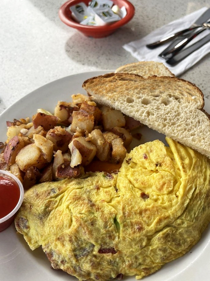 This isn't just an omelet&mdash;it's breakfast architecture. Golden eggs folded over savory fillings with those legendary home fries that could convert a potato skeptic.