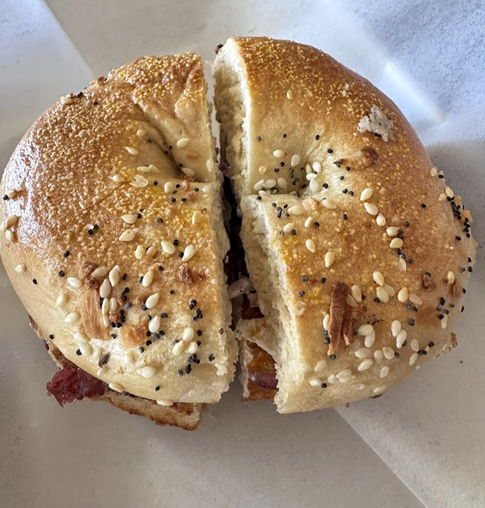 This isn't just a bagel sandwich; it's edible architecture &ndash; a perfect ratio of chewy bread to savory filling that makes fast food chains weep with inadequacy.