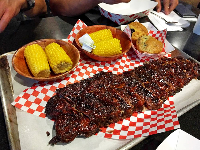 Glistening ribs that practically pose for their glamour shot alongside corn and cornbread. This metal tray holds more happiness than most people's vacation photos.