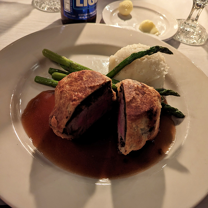 Behold the star attraction: Beef Wellington in its full glory, pastry-wrapped perfection surrounded by asparagus soldiers standing at attention in a pool of savory sauce.