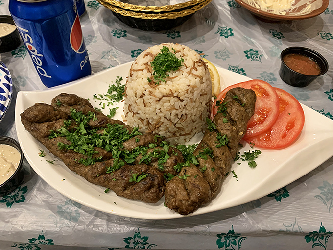 Beef kabab perfection &ndash; juicy, herb-flecked meat alongside aromatic rice and fresh tomatoes. This plate explains why locals make special trips across Orlando.