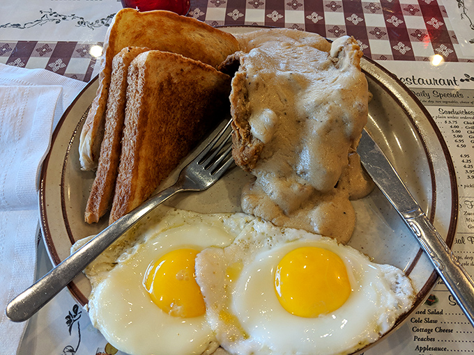 Behold the holy trinity of morning perfection: fluffy biscuits drowning in creamy gravy alongside perfectly cooked eggs.