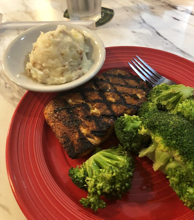 Blackened salmon that's worth the drive—perfectly seasoned, flaky yet moist, with sides of creamy mashed potatoes and vibrant broccoli.