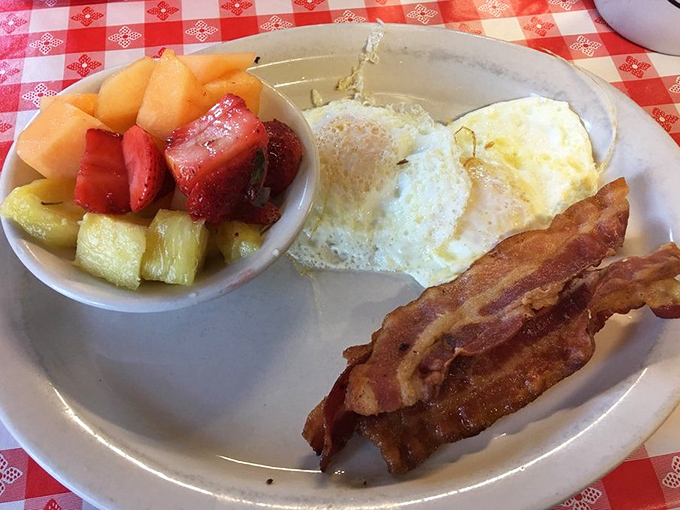 Simple perfection on a plate: eggs, bacon, and fresh fruit. The holy trinity of breakfast that never disappoints.