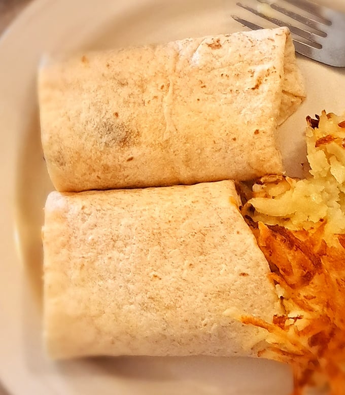 The legendary breakfast burrito &ndash; perfectly grilled tortilla hugging fluffy eggs and melted cheese, with crispy hash browns standing guard nearby.