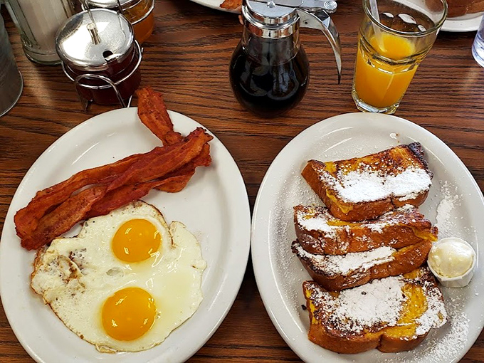 Sunny-side up perfection meets crispy bacon alongside French toast dusted with powdered sugar &ndash; breakfast's greatest hits on a single plate.