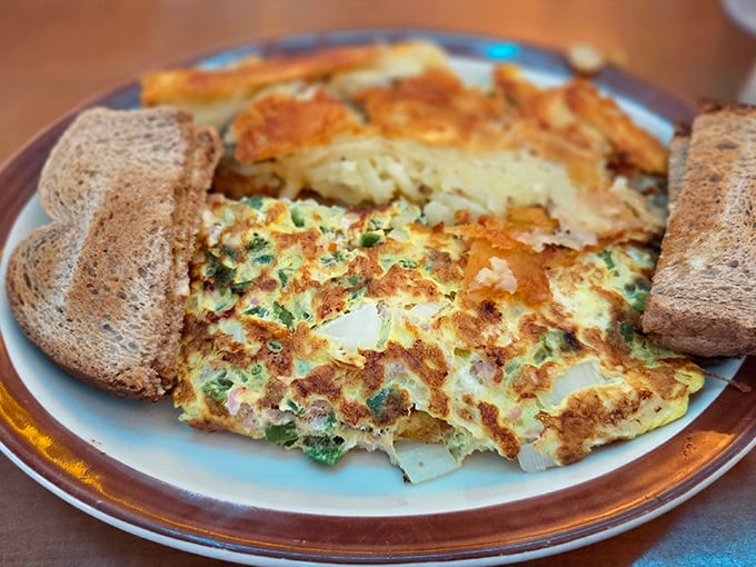 This omelet doesn't just sit on the plate &ndash; it lounges confidently between toast sentries, practically daring you not to photograph it first.