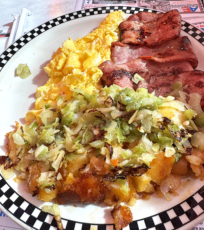 Breakfast nirvana achieved: golden scrambled eggs, crispy bacon, and home fries with grilled onions&mdash;the holy trinity of morning satisfaction.