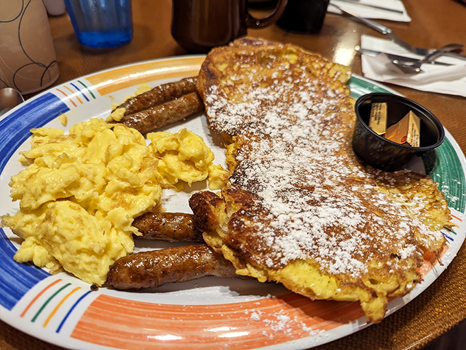 French toast that's dressed for success with powdered sugar, sausage links standing guard, and eggs that practically glow with morning optimism.