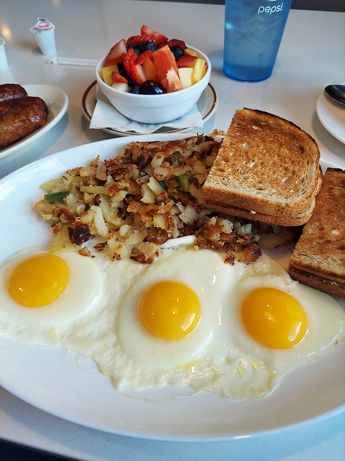 Three sunny-side-up eggs, perfectly crispy hash browns, and toast – the breakfast trinity that's been solving problems since the dawn of diners.
