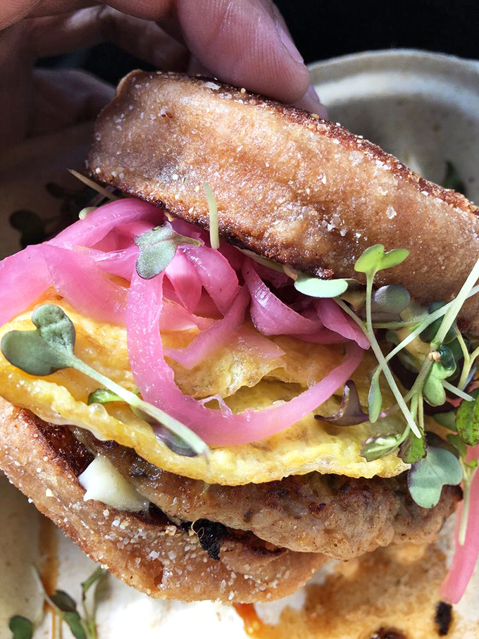 Behold the breakfast sandwich in its natural glory&mdash;a perfect storm of fluffy eggs, vibrant pickled onions, and microgreens that make health food feel like rebellion.