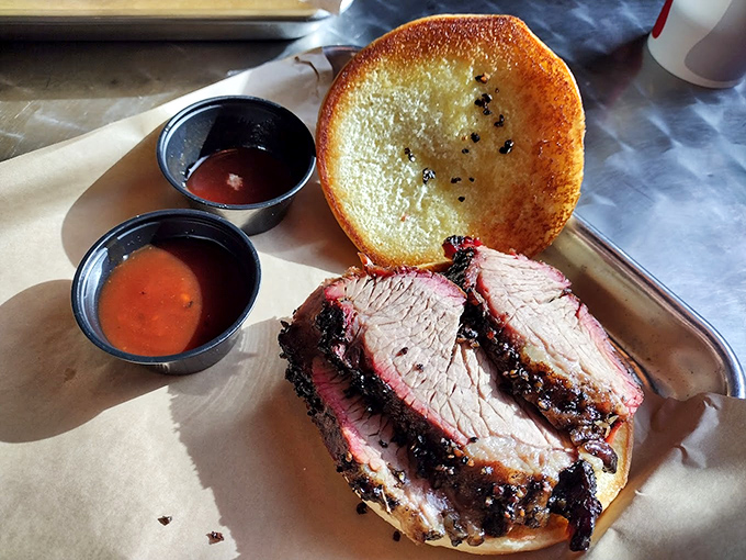 This brisket sandwich isn't just food; it's edible poetry. The pink smoke ring and charred bark tell stories of patience and fire.