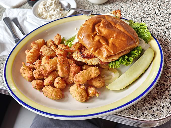 This isn't just a sandwich; it's an architectural masterpiece of crispy chicken, fresh lettuce, and a perfectly toasted bun, with tater tots standing guard.
