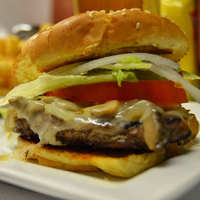 Behold burger perfection: melted cheese cascading over a substantial patty, fresh veggies adding crunch, and a bun that's up to the important job of holding it all together.