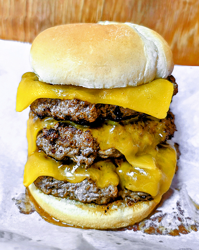 Behold the triple-decker masterpiece that haunts dreams. Those perfectly melted cheese cascades should have their own theme music.