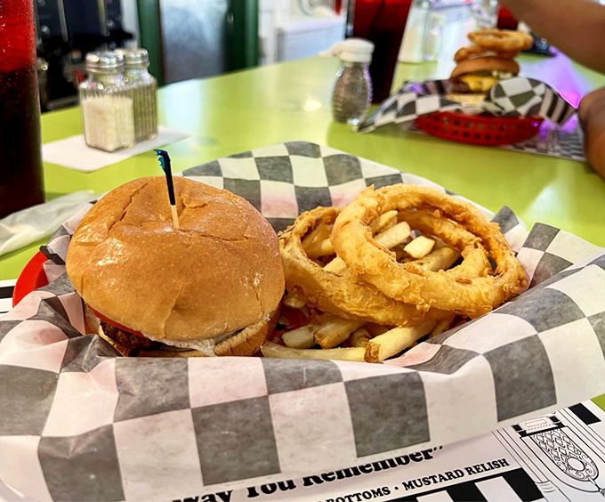 This isn't just lunch; it's a masterclass in diner perfection. The holy trinity of cheeseburger, fries, and onion rings presented on checkered paper—as God intended.