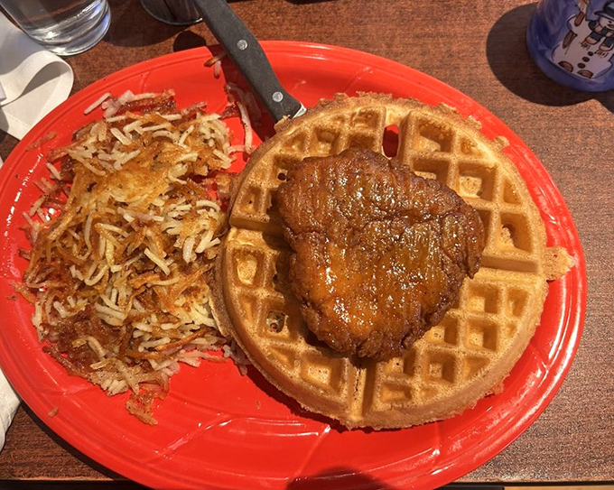 The star of the show: golden-brown chicken perched atop a perfect waffle, with crispy hash browns standing by. This is what breakfast dreams are made of.