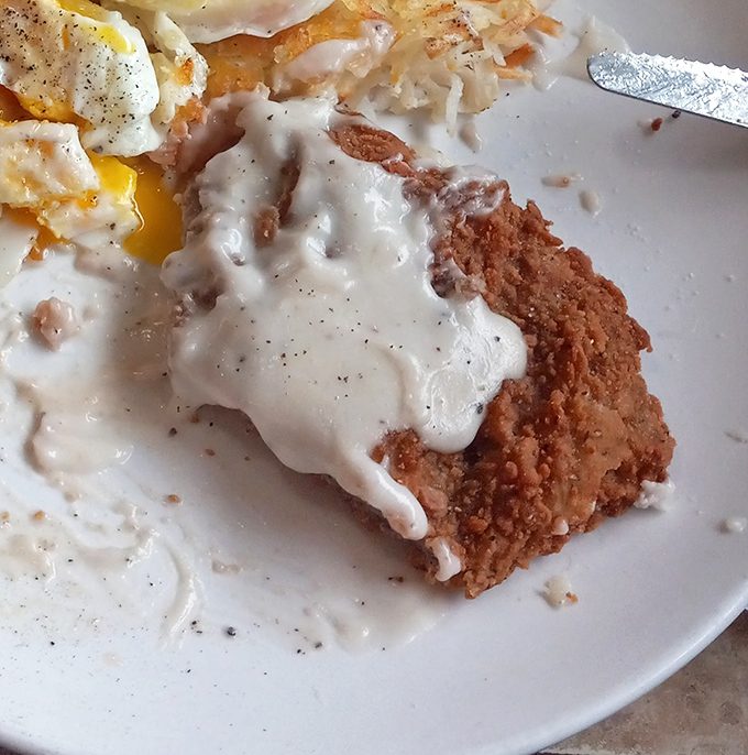 Behold the crown jewel: chicken fried steak with pepper-speckled gravy cascading over crispy edges. The runny egg yolk is nature's perfect sauce.
