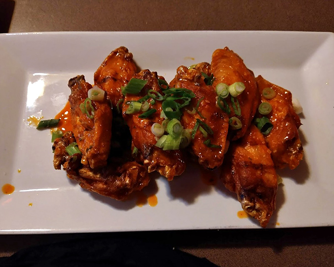 These wings aren't just good, they're tell-your-friends-and-ruin-your-shirt good. Crispy, saucy perfection garnished with scallions and zero regrets.