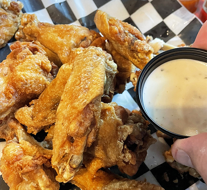 Golden-brown wings that achieve the holy grail of wing perfection: crispy exterior, juicy interior, and enough sauce to make napkins mandatory but worth it.