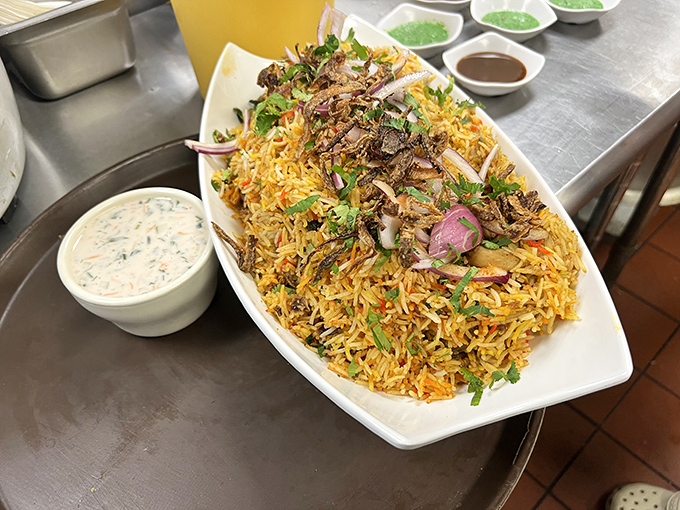 This mountain of biryani isn't just rice—it's an aromatic expedition topped with crispy onions and fresh herbs that demands to be explored.