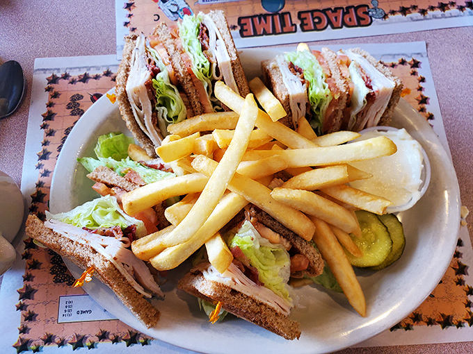 The legendary club sandwich arrives like edible architecture&mdash;perfectly stacked layers secured with toothpicks and surrounded by golden fries that demand immediate attention.