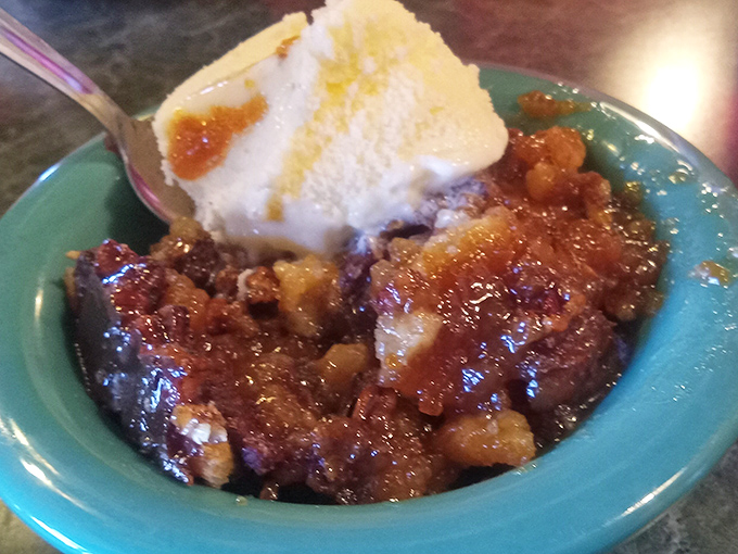 The star of our show: that heavenly cobbler with melting ice cream creating rivers of vanilla goodness through bubbling fruit and golden crust. Spoon poised for the perfect bite.