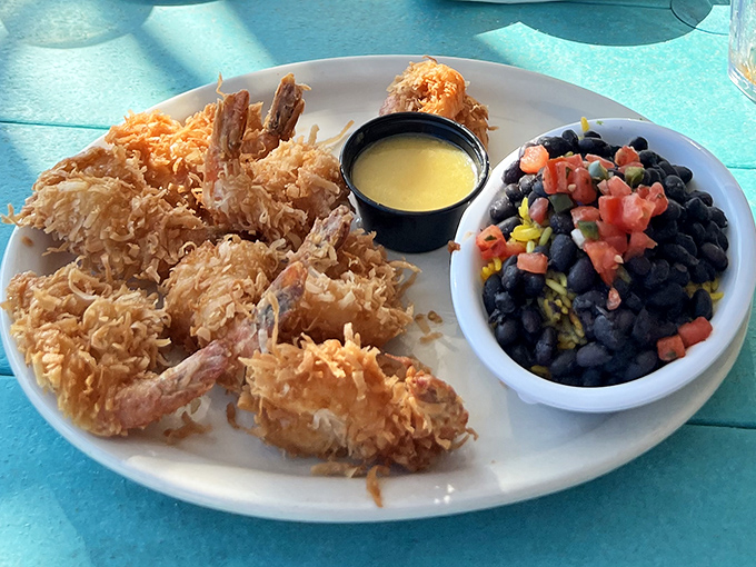 Golden-battered coconut shrimp that crunch like nature's perfect soundtrack. Paired with black beans that Florida does right—this plate is worth crossing county lines for.