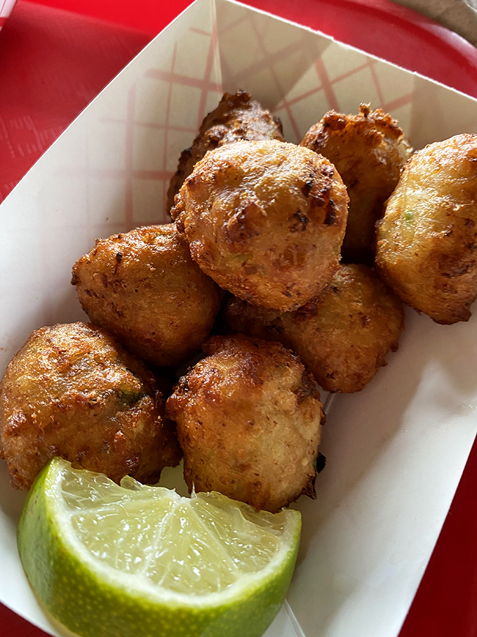 Golden-brown conch fritters that crunch like your favorite childhood memory, served with a lime wedge that cuts through the richness perfectly.