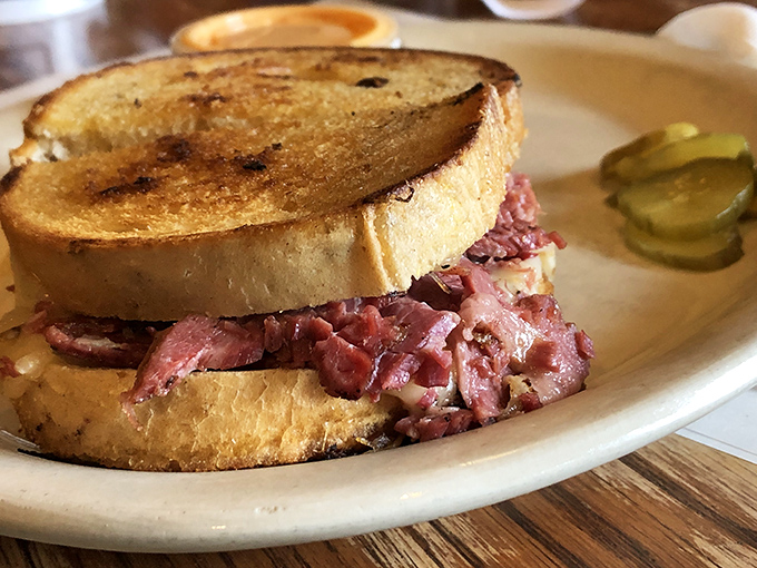 The Reuben sandwich in its natural habitat&mdash;a mountain of corned beef nestled between grilled rye, with a pickle standing guard.