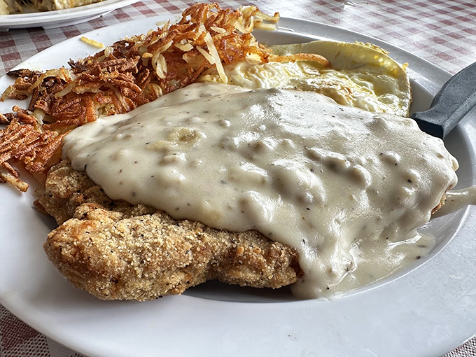 Country fried steak swimming in peppery gravy with crispy hash browns&mdash;proof that heaven exists and it's on this plate.