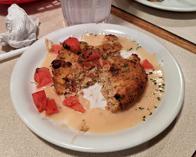 This crab cake doesn't just sit on the plate—it lounges in a pool of velvety sauce, surrounded by fresh tomatoes like a seafood celebrity on vacation.