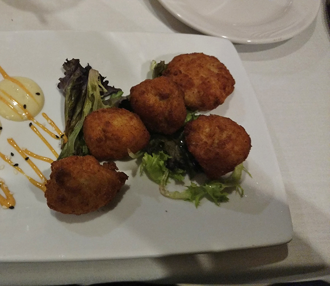 These golden-brown crab cake bites aren't just appetizers &ndash; they're little spheres of seafood joy that might make you forget your table manners.