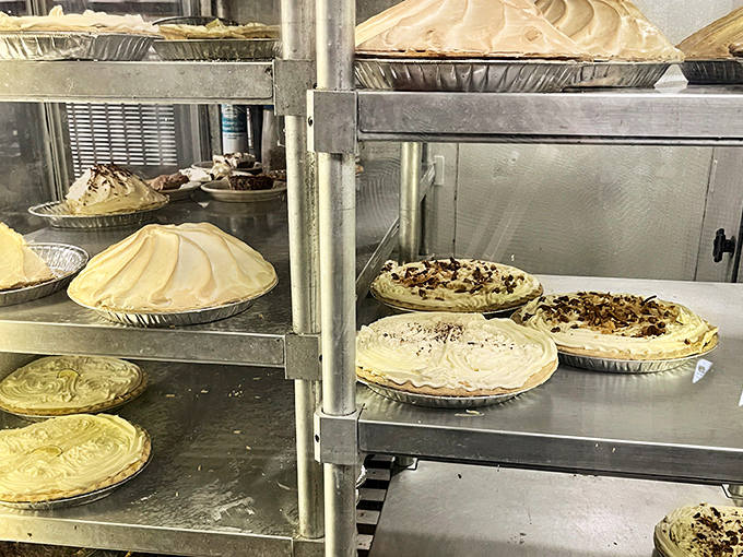 Behind glass doors lies pastry paradise - cream pies stacked like edible architecture awaiting discovery.