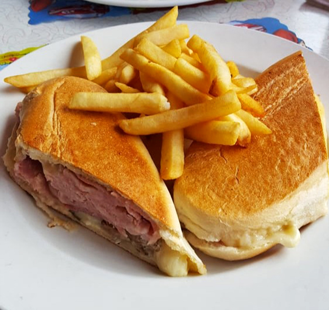 The Cuban sandwich arrives like a diplomatic mission of flavor &ndash; ham, roasted pork, and Swiss cheese negotiating perfect harmony between two crispy slices of bread.