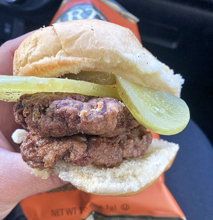 A cross-section reveals the beautiful simplicity: crispy-edged patty, tangy pickle, sharp onion, and pillowy bun. Minimalism never tasted so good.