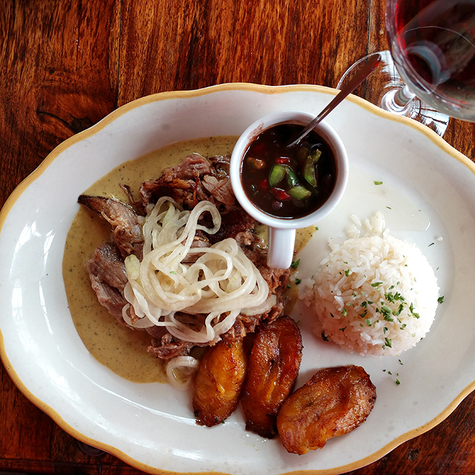 Slow-roasted pork with crispy onions and plantains that could make a grown person weep. This plate doesn't just feed you&mdash;it hugs you from the inside out.