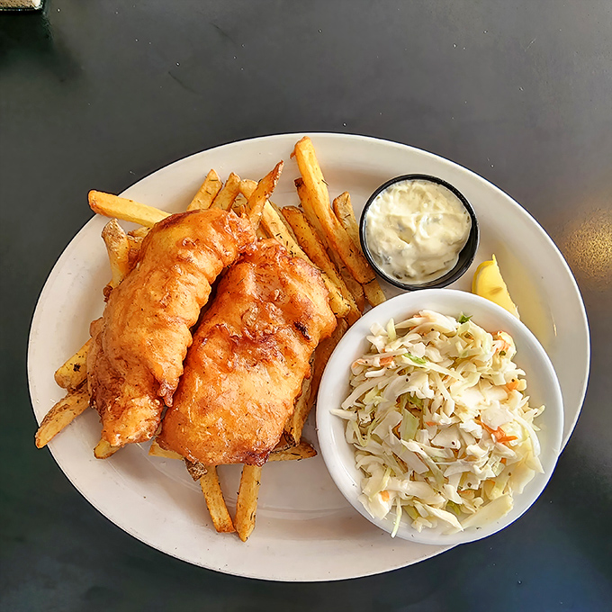 Golden perfection arrives: crispy battered fish alongside fries that would make your grandmother weep with joy.