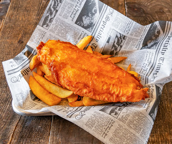 Golden, crispy batter hugging flaky white fish atop chunky chips&mdash;newspaper wrapping completes this authentic British masterpiece.