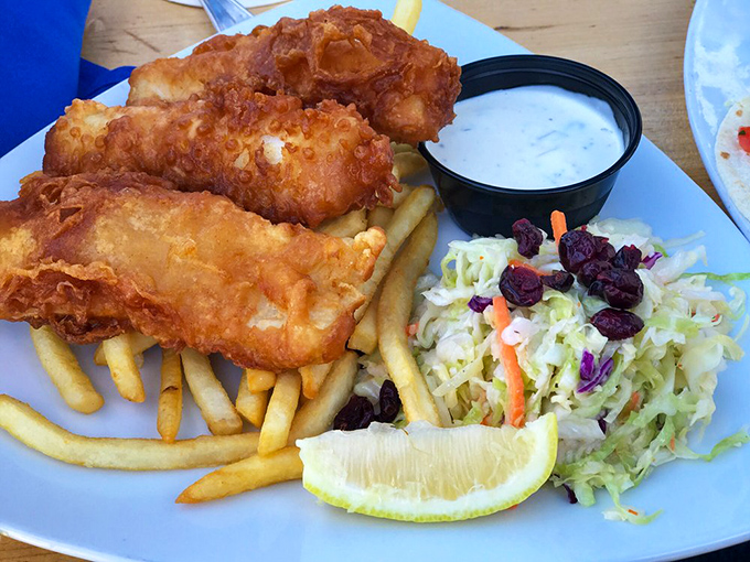 Golden-battered fish that shatters with each bite, alongside crispy fries and tangy slaw &ndash; this isn't just fish and chips, it's edible sunshine.