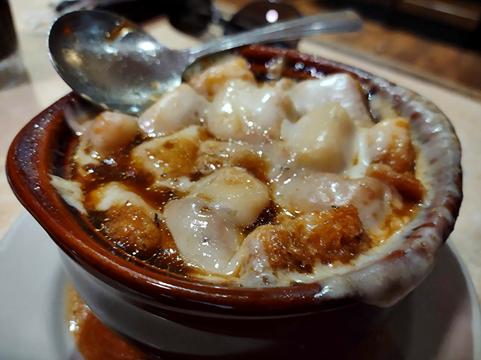 The legendary French onion soup arrives in its traditional crock, a bubbling masterpiece of caramelized onions and melted cheese that demands a moment of silent appreciation.