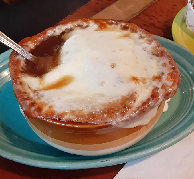 Behold the golden crown of melted cheese that transforms simple onion broth into pure liquid comfort.