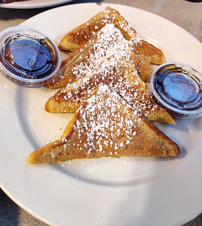 The French toast arrives like a golden revelation&mdash;perfectly caramelized triangles dusted with powdered sugar that make you question all other breakfast choices.