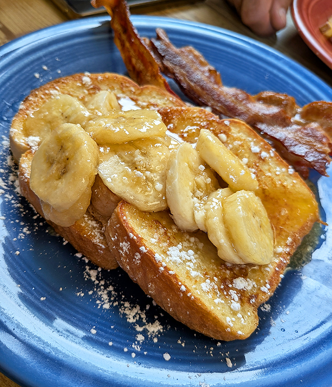 French toast nirvana achieved! Golden-brown perfection topped with bananas and a dusting of powdered sugar that would make even breakfast skeptics weak at the knees.