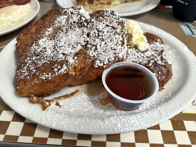 French toast nirvana exists, and here's the proof: perfectly golden slices dusted with powdered sugar, a dollop of butter, and maple syrup on standby.